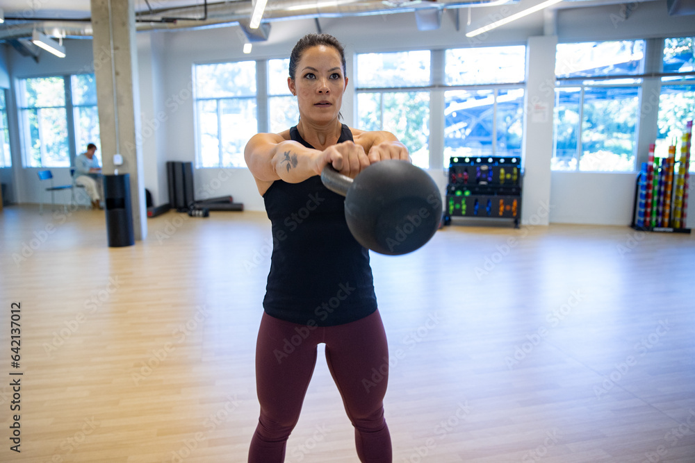 Strong woman working out in gym with kettle ball weight. She is ...