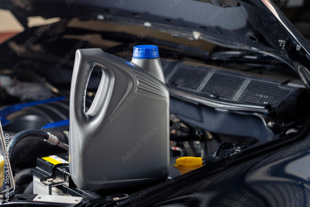 Car lubricant gallon or from gray bottle on engine background Oil ...