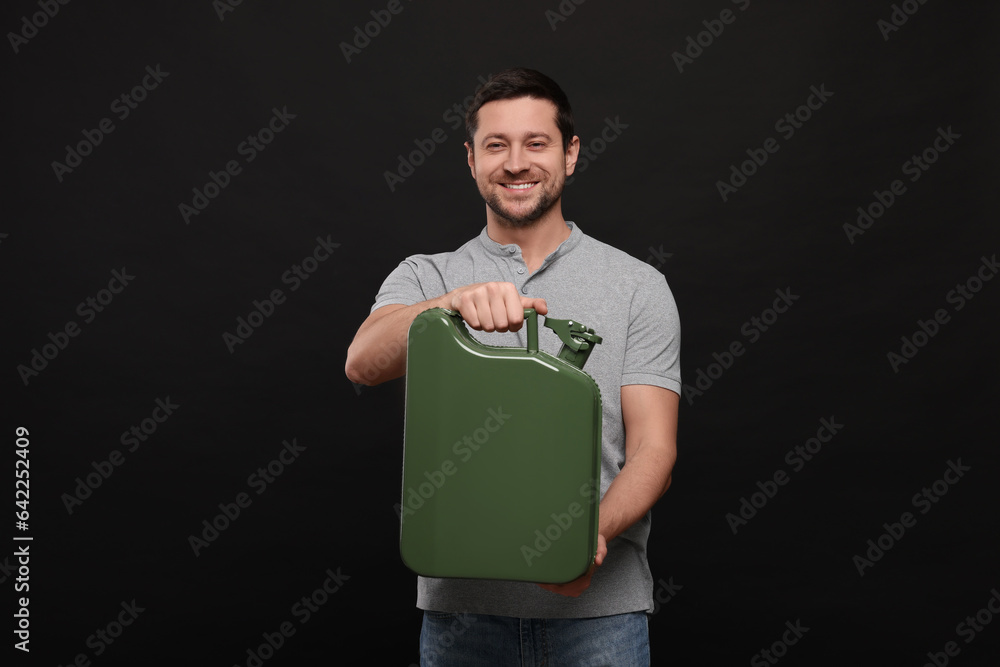 Handsome man holding khaki metal canister on black background Stock ...