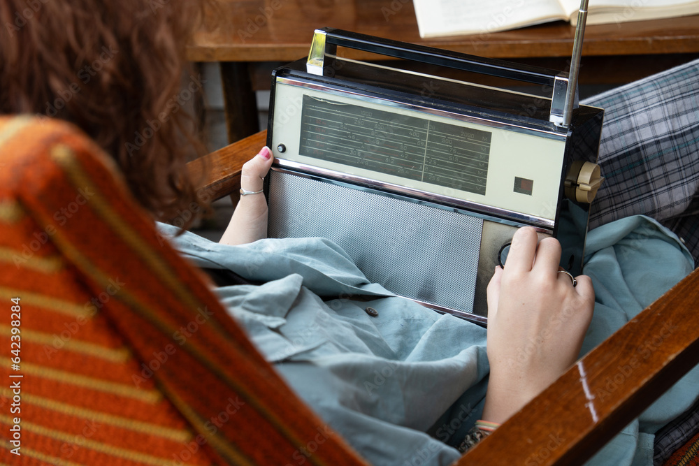 Girl sitting in a armchair searching for a radio station frequency or ...