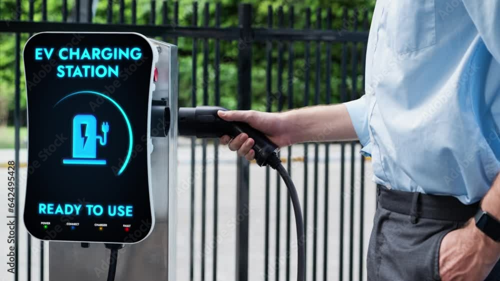 Businessman pull out EV charger from charging station to recharge ...