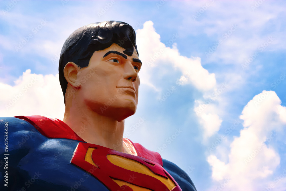 Low angle face shot of a metal statue of Superman. The statue has a red ...