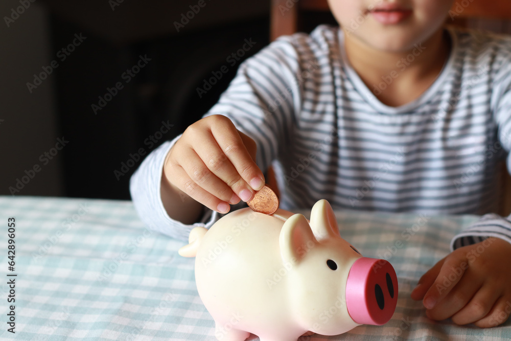 Chid holding piggy bank. Child boy putting insert coins in the piggy ...