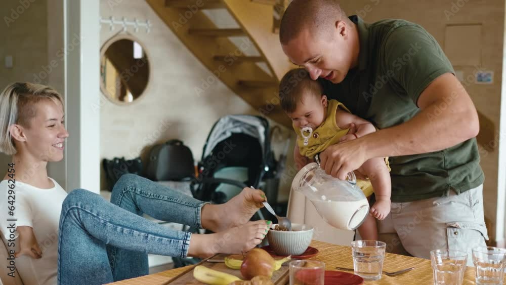 Happy young family with a litle baby is preparing breakfast at the ...