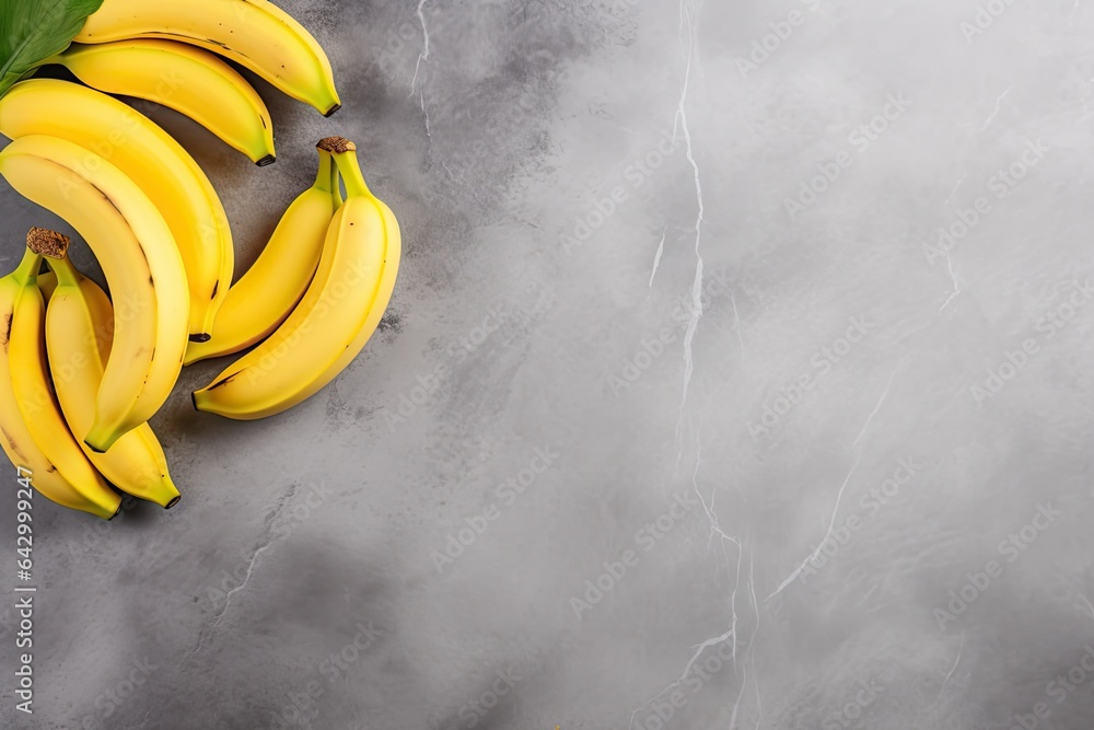 Two bright yellow bananas are placed on a gray surface, creating a ...