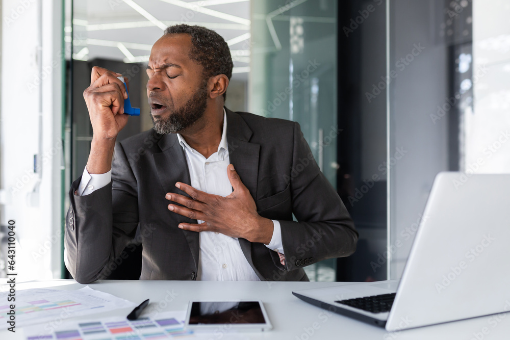 Sick man inside office with asthma using inhaler to ease breathing ...