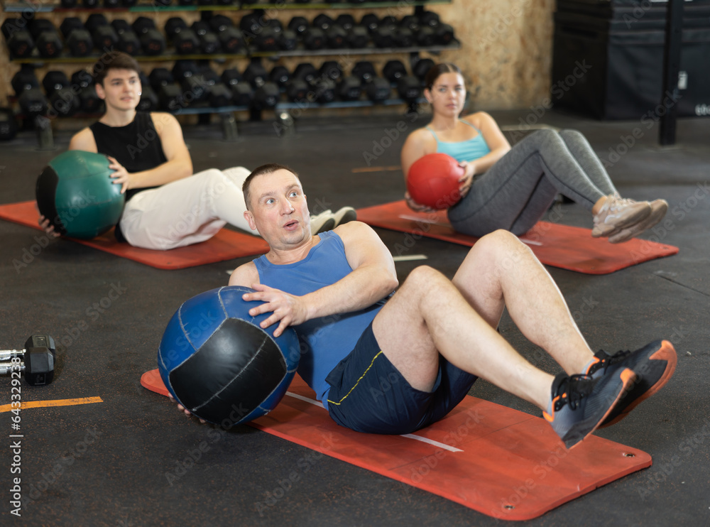 Focused adult man taking part in high-intensity group training session ...