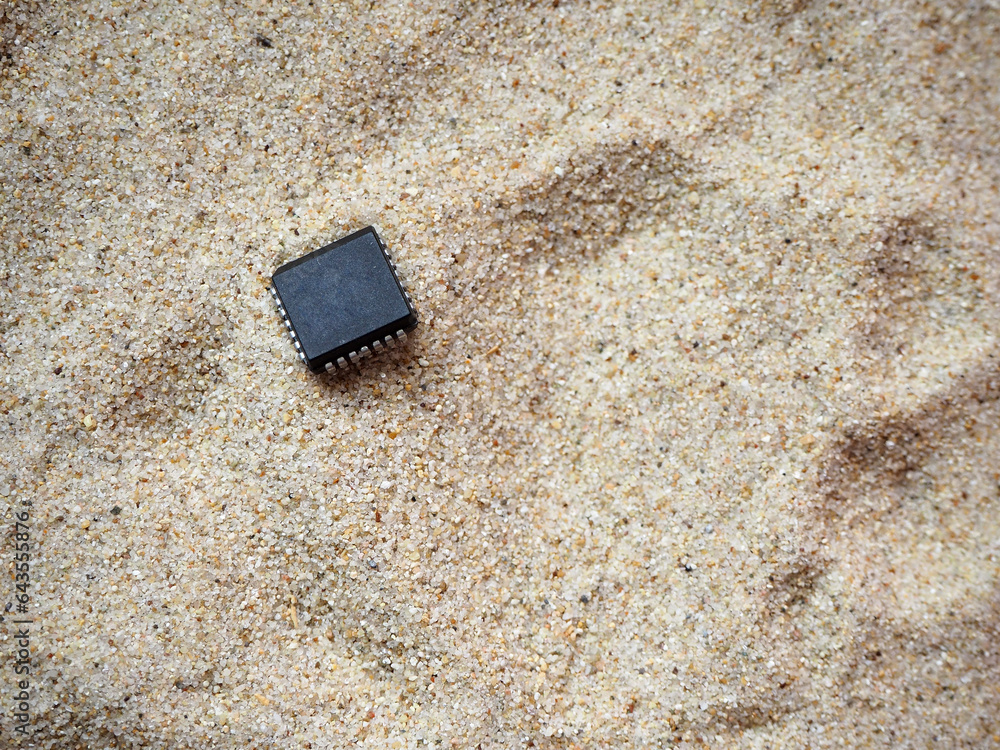 Microchip buried in the sand. Semiconductor industry, processor manufacturing concept background ...