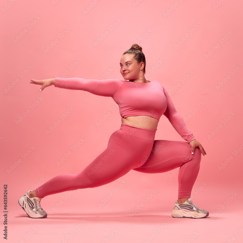 Full body portrait of young plus size sporty woman in pink top and ...