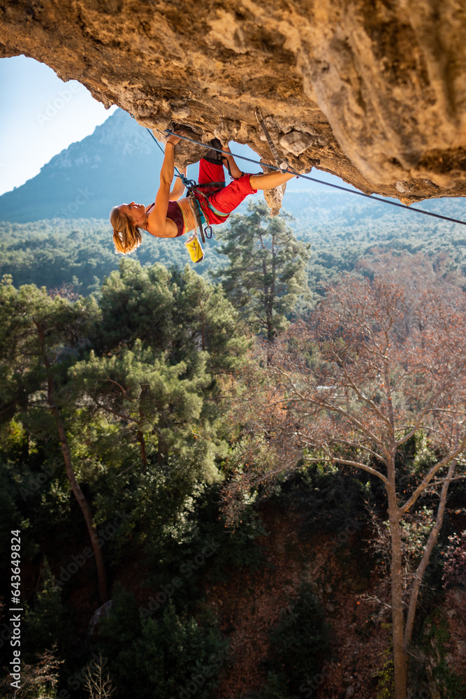 girl rock climber climbs a rock against the backdrop of a forest and ...
