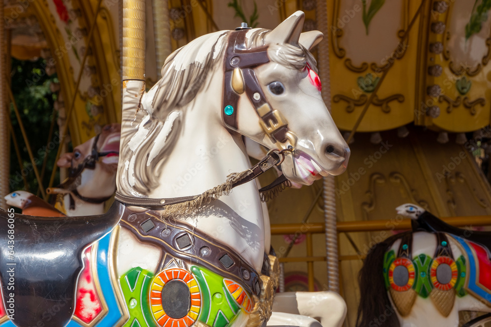 Old French carousel in a holiday park during sunny day. Horses on a ...