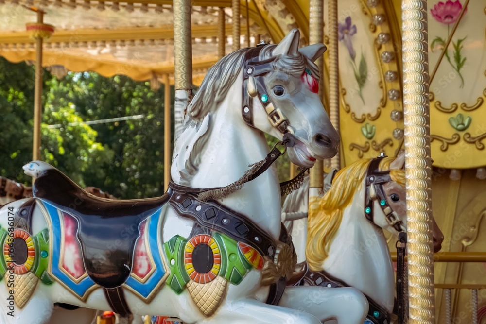 Old French carousel in a holiday park during sunny day. Horses on a ...