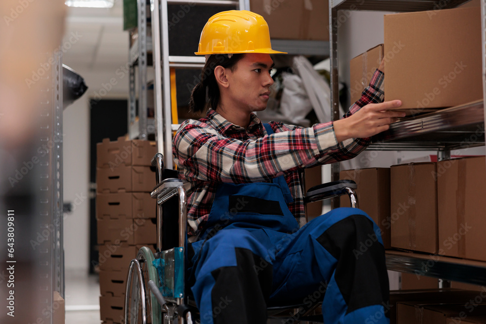 Storehouse employee in wheelchair taking cardboard box for order ...