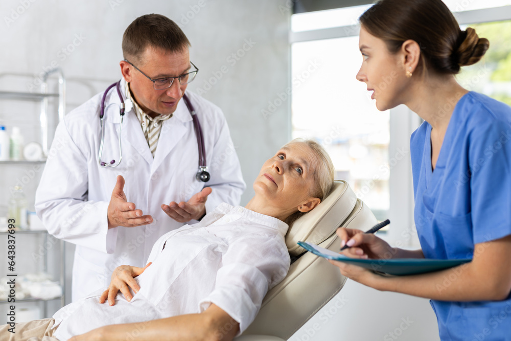 Professional doctor conducting questionnaire of senior woman lying on ...