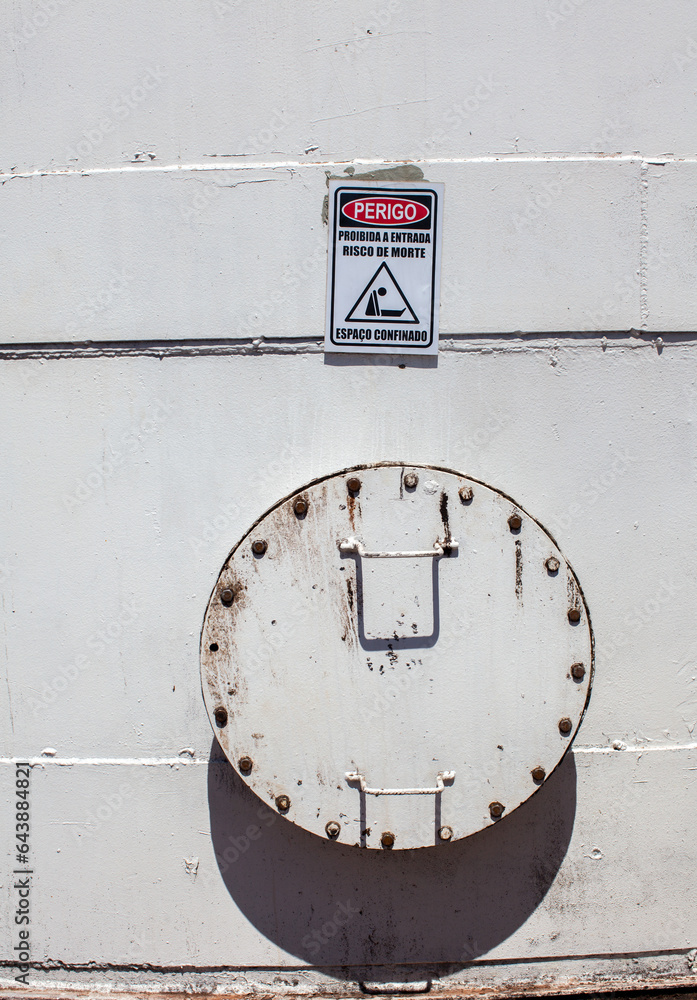 White industry tank with confined space entrance with warning sign ...