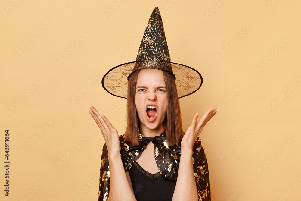 Angry aggressive young girl wearing black halloween garment and cone ...