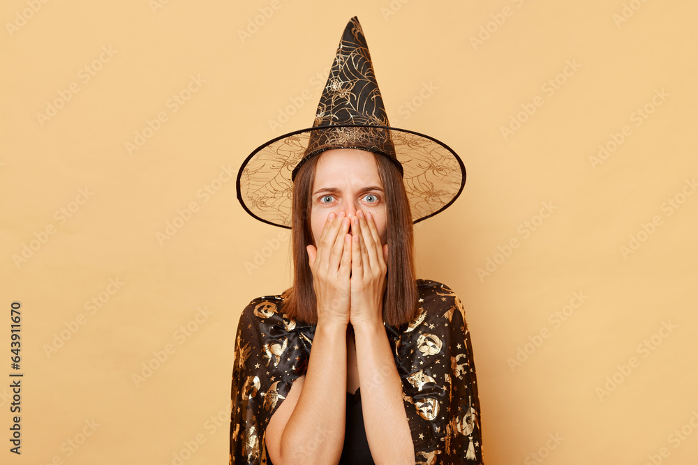 Shocked scared young girl wearing black halloween garment and cone ...