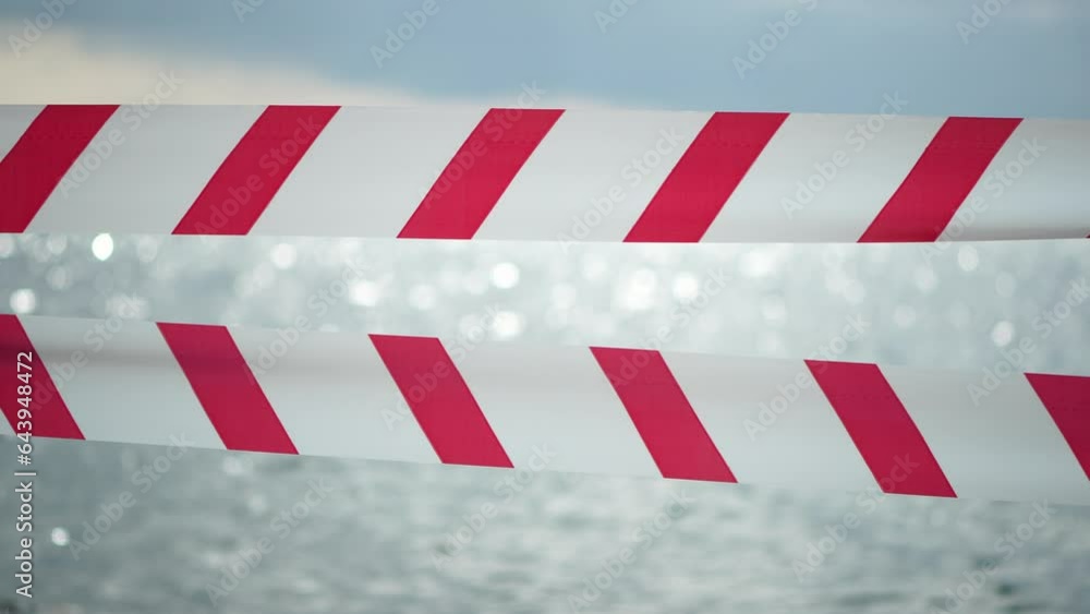Red white warning tape barrier ribbon swinging in the wind across ...