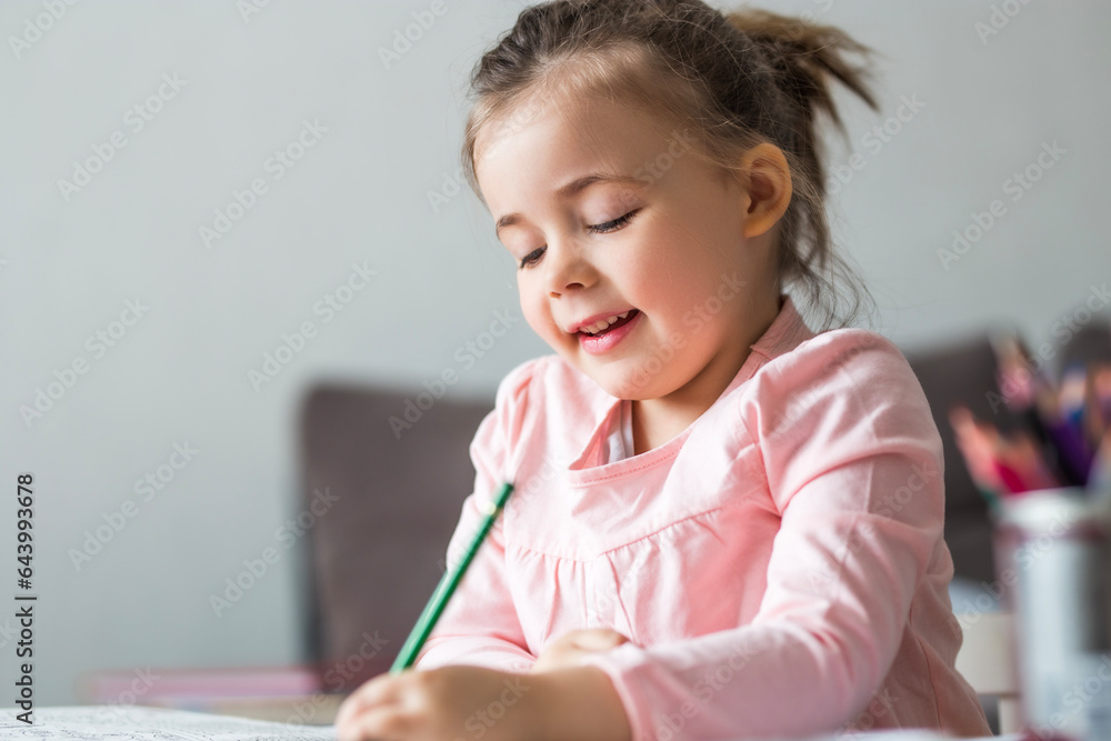 Cute smiling little girl write homework at desk at home. Happy ...