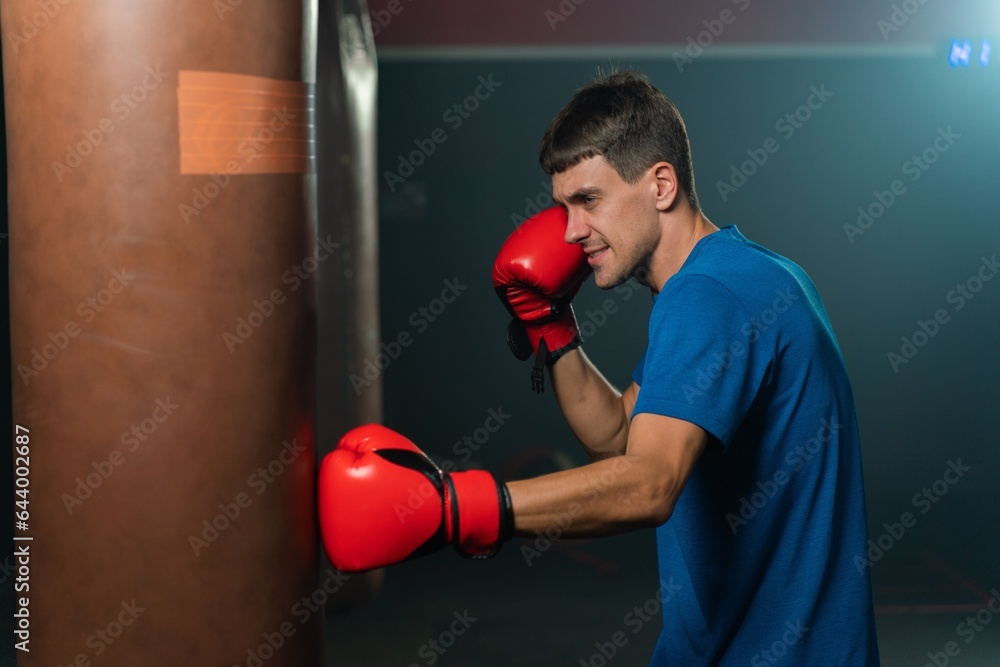 Tall white man in a blue tee shirt engages in a focused boxing punching ...