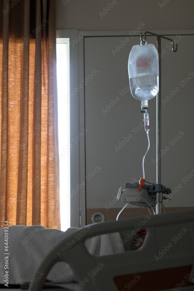 A stand with drip bag beside the bed at hospital. The saline solution ...