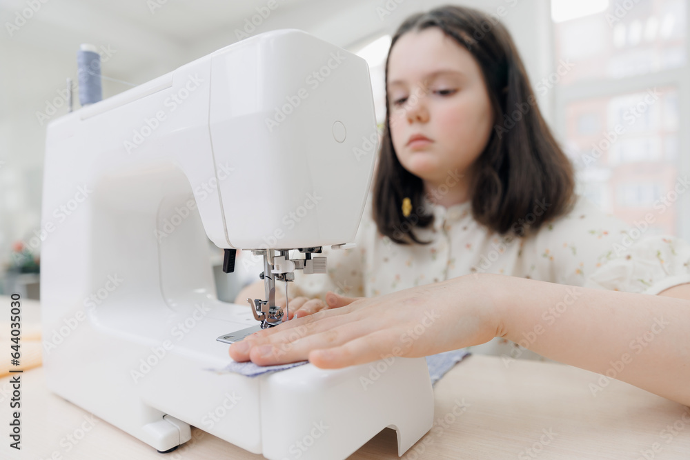 Little girl learns to sew, working with modern sewing machine on ...