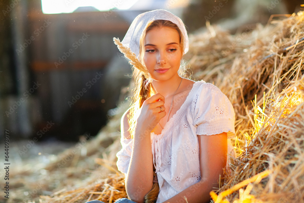 Beautiful blonde girl with braided hair in white rural clothes sitting ...