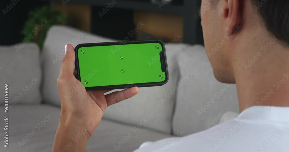 Male hand using smartphone with green screen mock-up at home, tapping ...