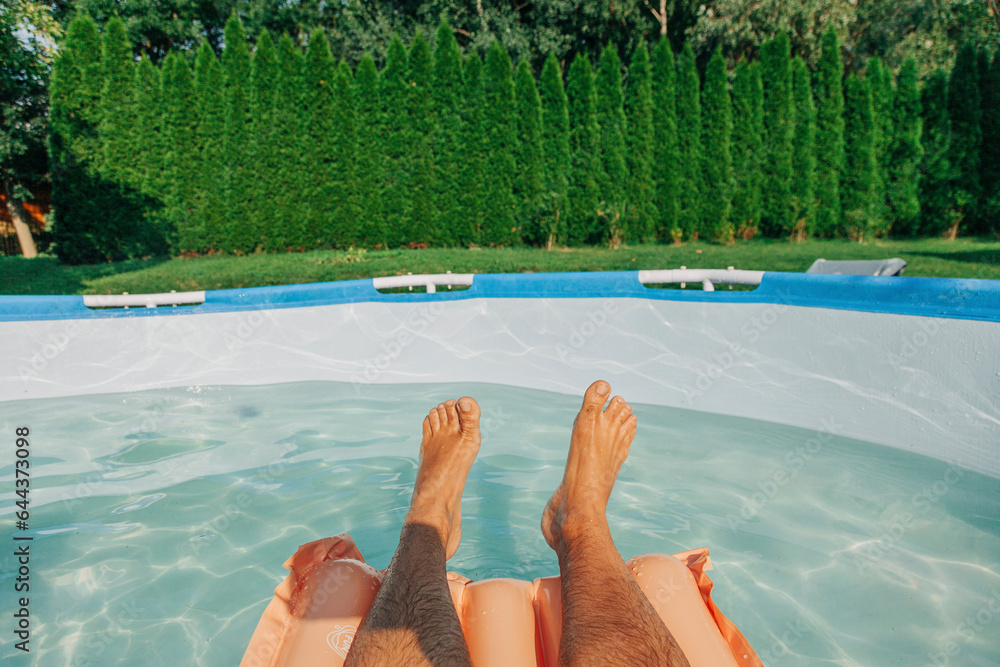 Legs of man floating in wading swimming pool at backyard Stock Photo ...
