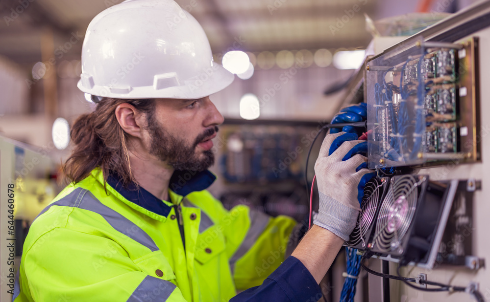 A male electrician works in a switchboard with an electrical connecting ...