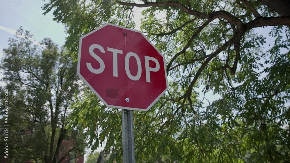 Handheld slow motion shot rotating around red stop sign by street ...
