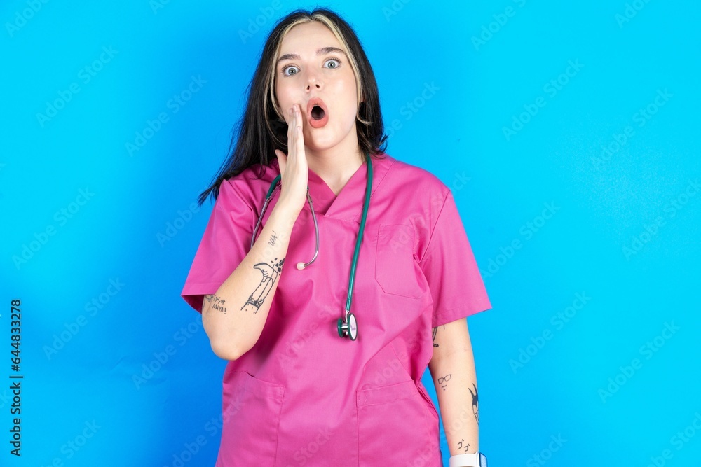 Shocked Young caucasian doctor woman wearing pink medical uniform looks ...
