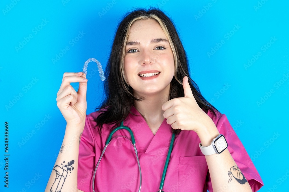 Young caucasian doctor woman wearing pink medical uniform holding an ...