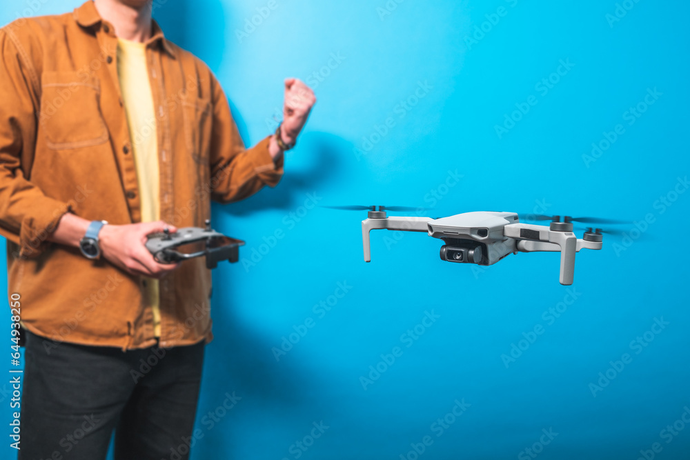 Smiling young man celebrating piloting a drone in flight with a remote ...