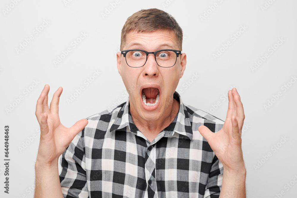 Portrait of angry young man screaming holding hands in furious gesture ...