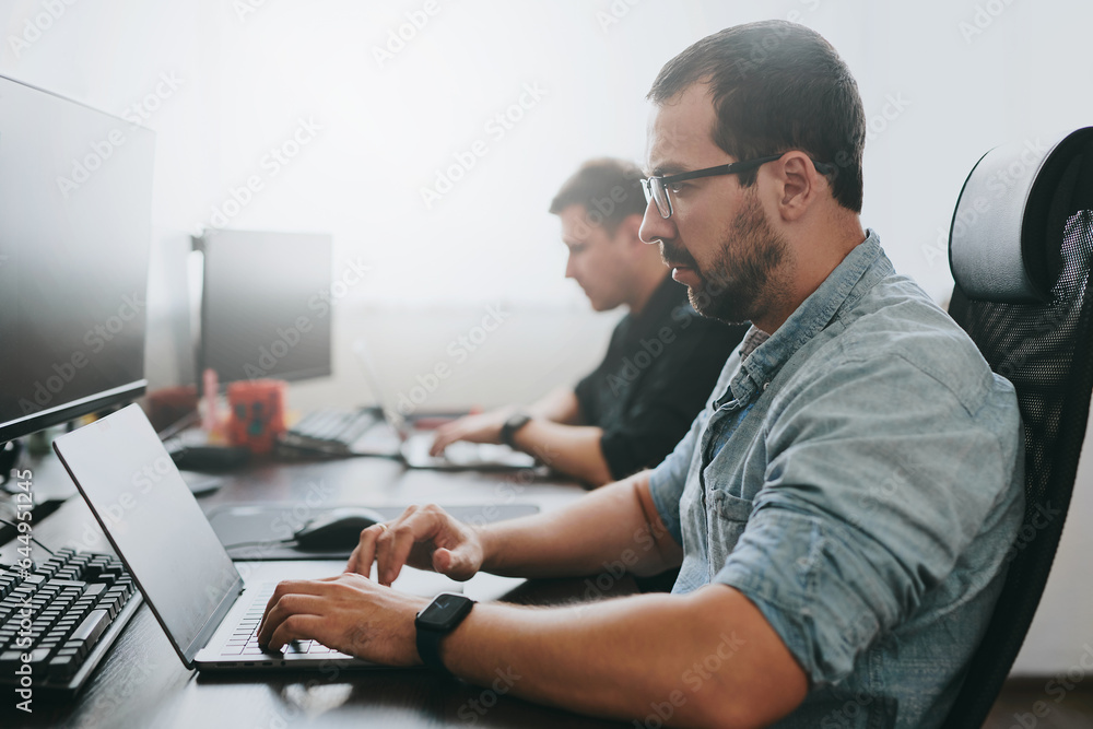 Portrait of two professional male programmers working on computer in ... Portrait of two professional male programmers working on computer in ...