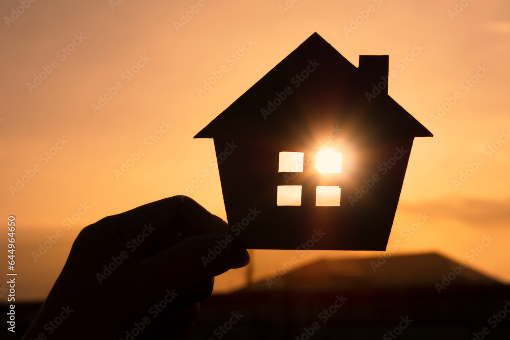 Hands holding paper house on sunset sky, family home, homeless housing ...