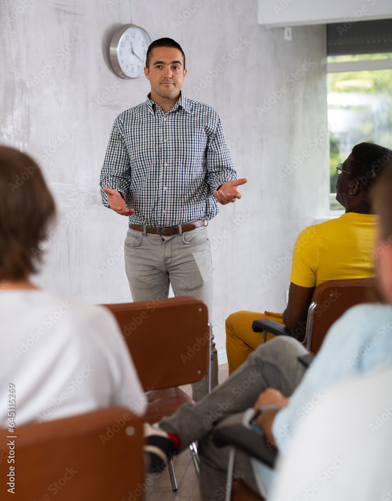 Positive male tutor giving lecture as part of educational program while ...