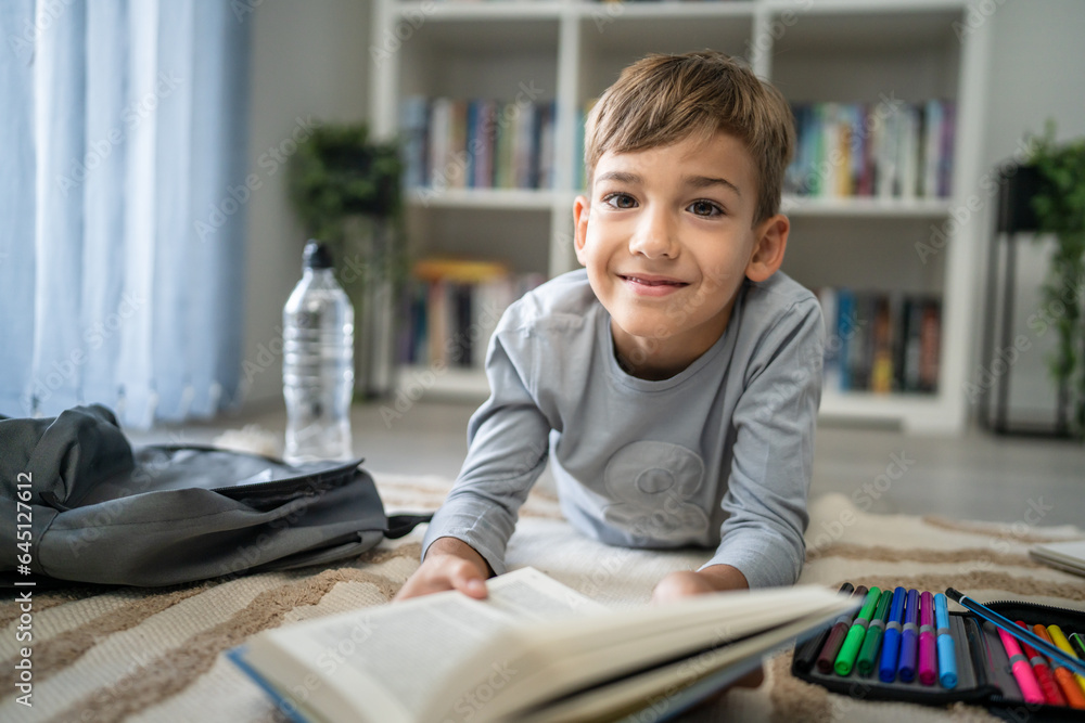 caucasian boy pupil student read book at home on the floor study learn ...