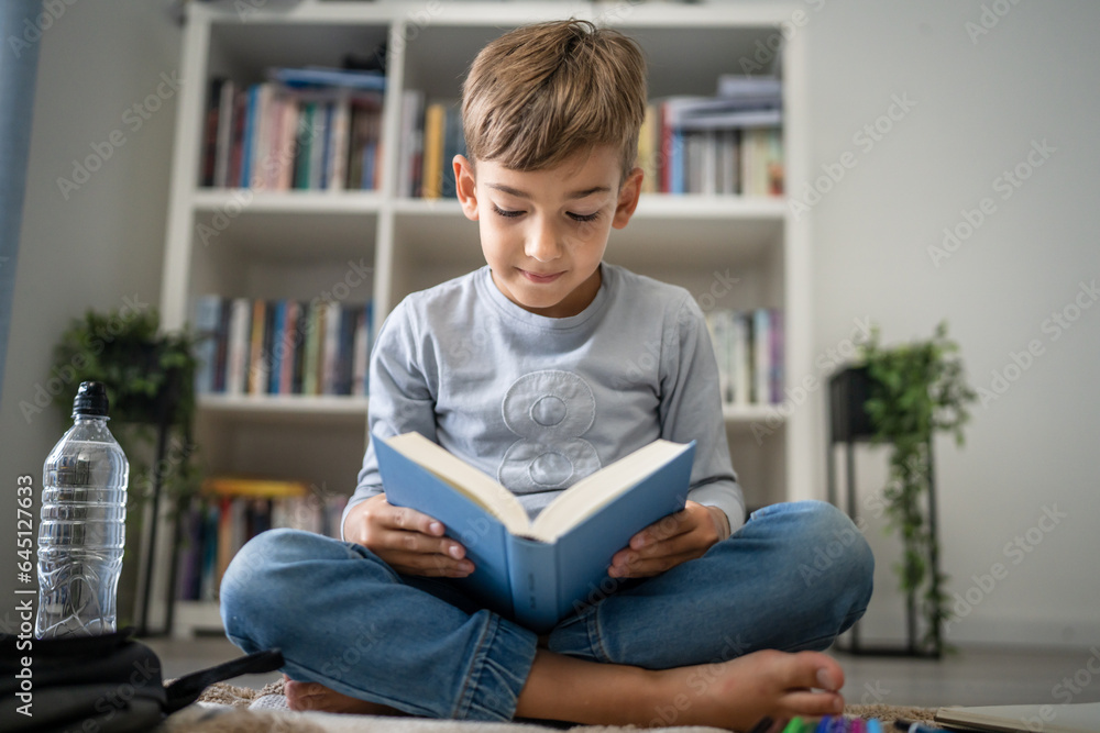 caucasian boy pupil student read book at home on the floor study learn ...