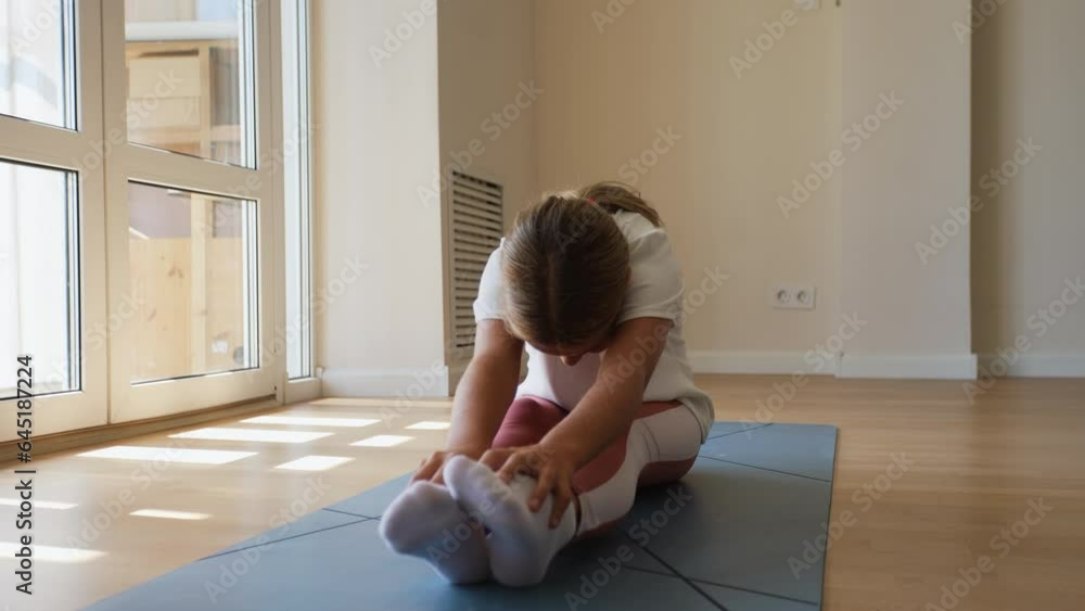 Flexible little kid girl sitting on floor and stretch bending forward ...