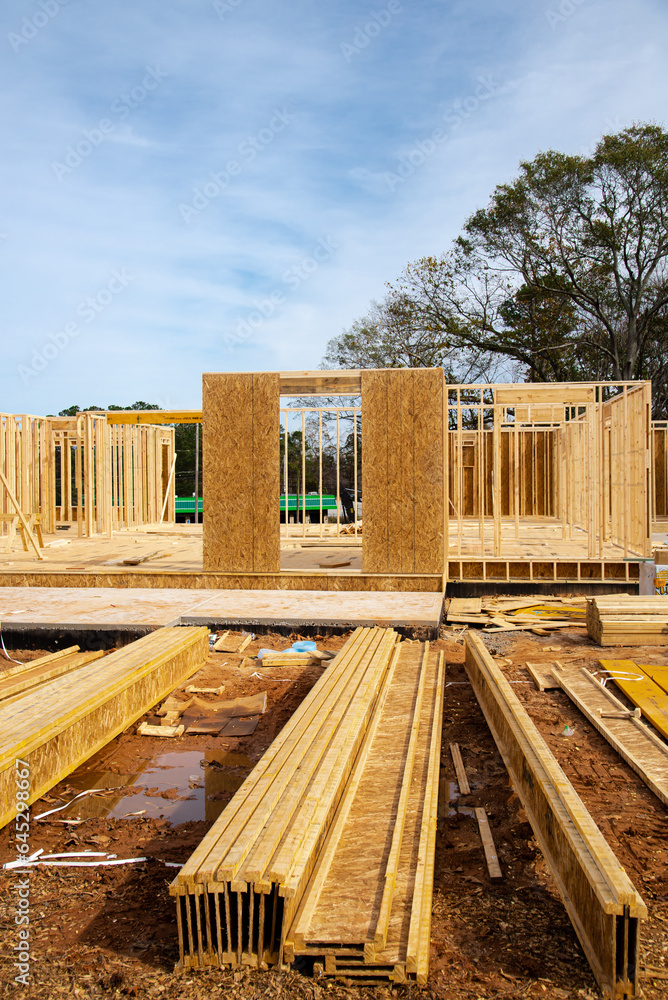 Stack of lumbers in front of timber frame house with post, beam, OSB ...