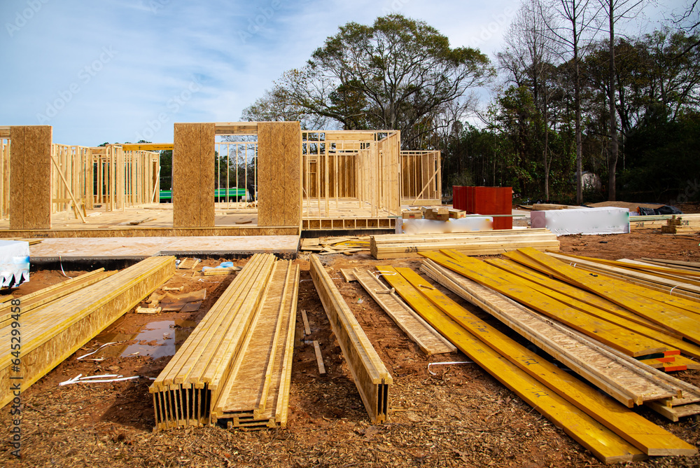 Stack of lumbers in front of timber frame house with post, beam, OSB ...