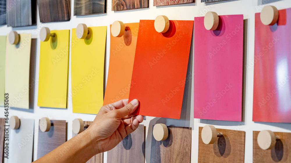 Designer hand picking colorful laminate sheet on material swatch wall ...