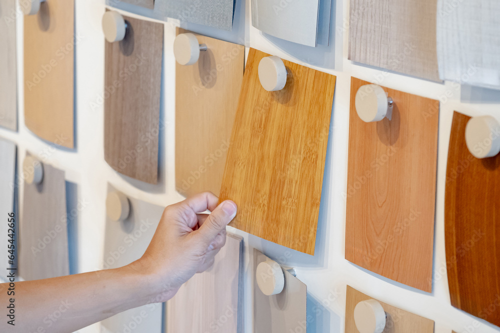 Designer hand picking wood samples board from material swatch wall ...