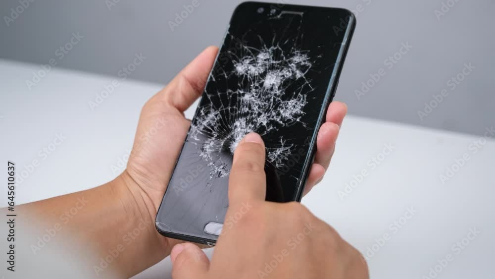 Female hand holding a smartphone with a broken screen and touching the ...
