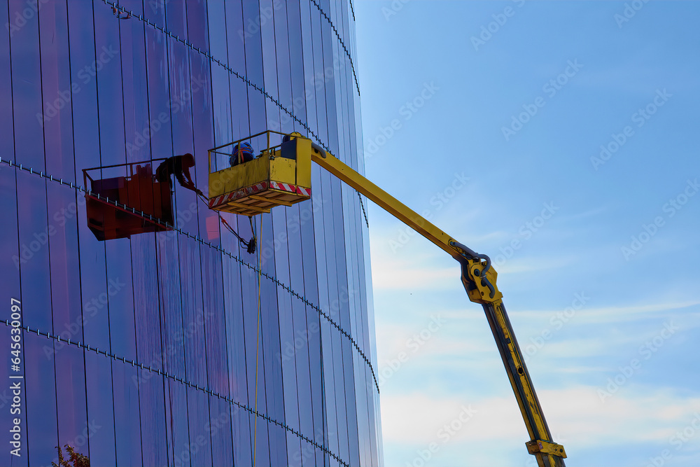 Window cleaning work at height on a lifting platform. Washing office ...