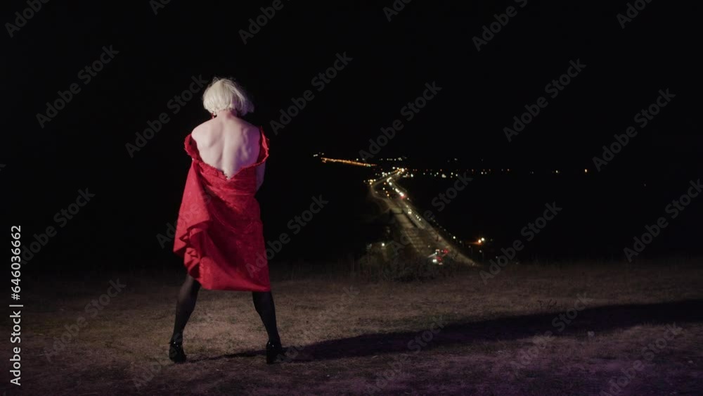 Extravagant drag queen in red dress lifts up her skirt and shows her ...