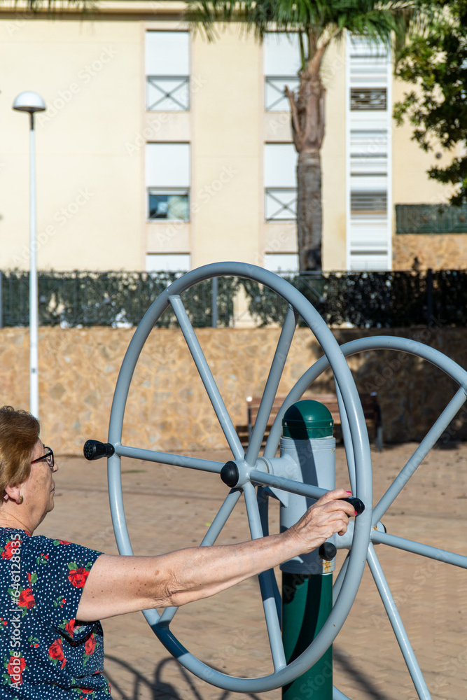 Senior woman exercises by moving a spinning wheel in the bio healthy ...