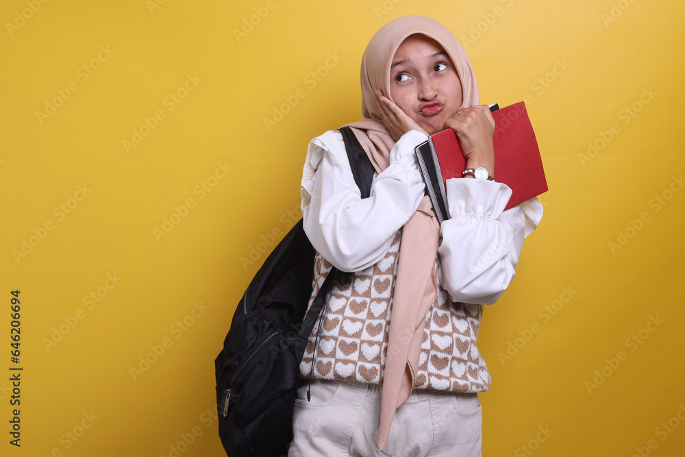Young Asian muslim student girl in hijab holding book and touch cheek ...